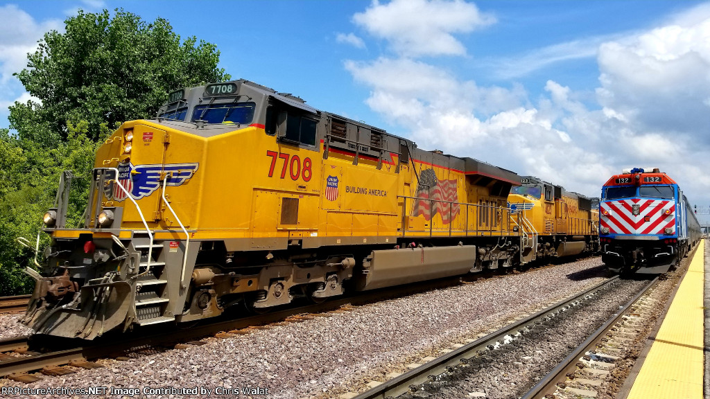 UP #7708 races west past Metra #132 at the Elburn, IL station.